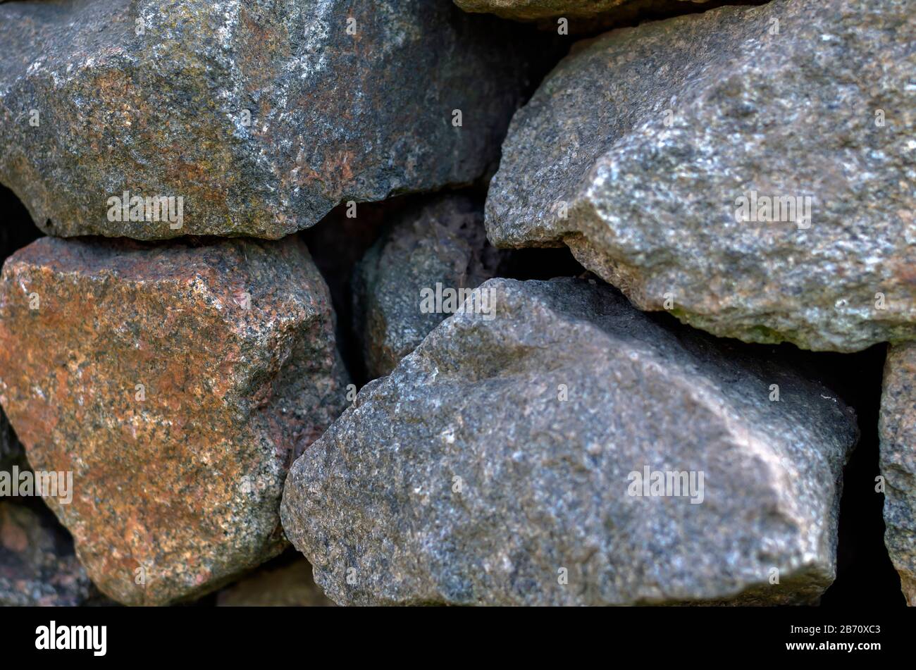 Rough uncouth granite cobbles. Granite stones stacked one on one. Large ...