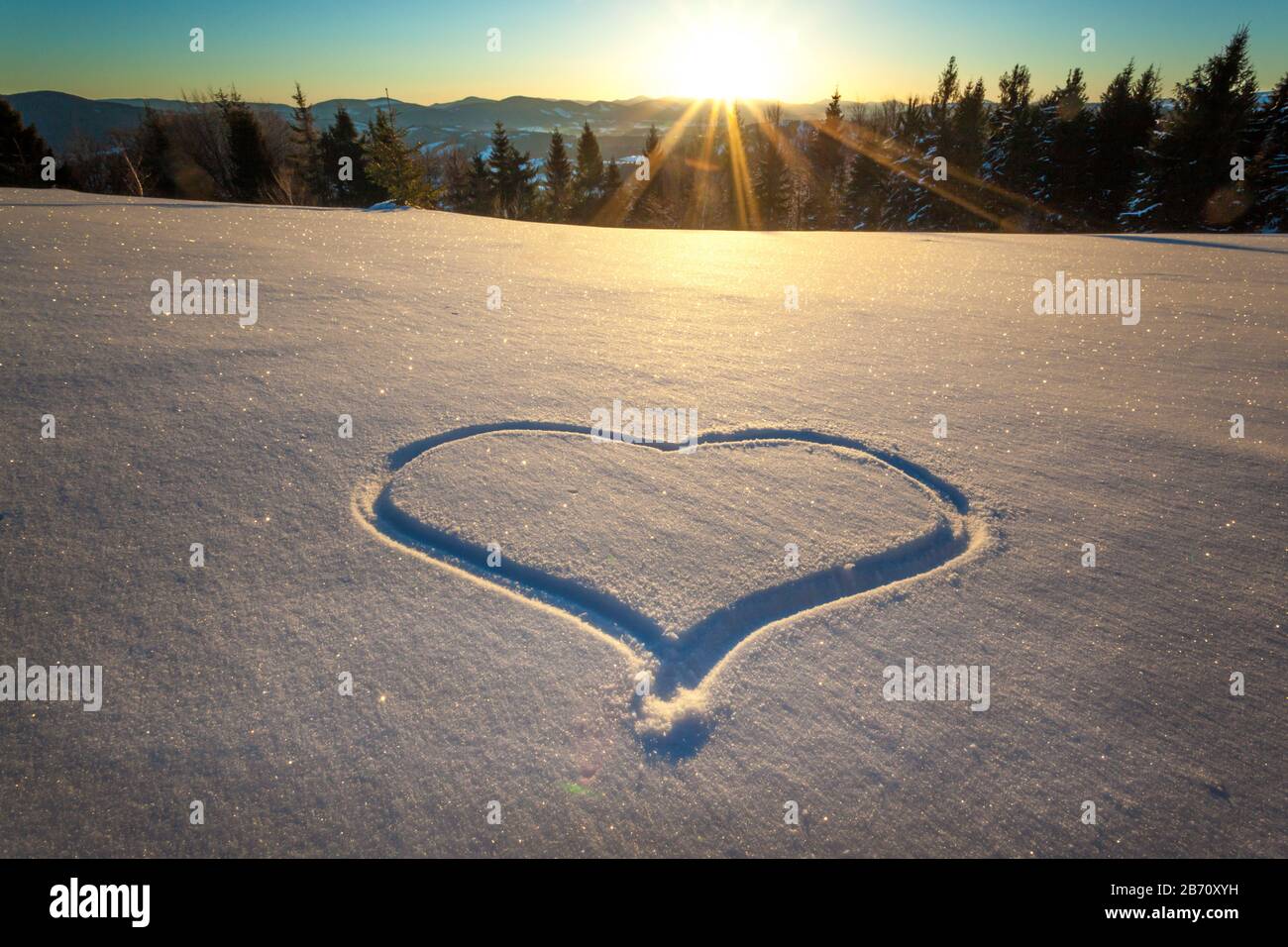 Heart trampled on the snow with feet in a snowdrift on a hillside with ...