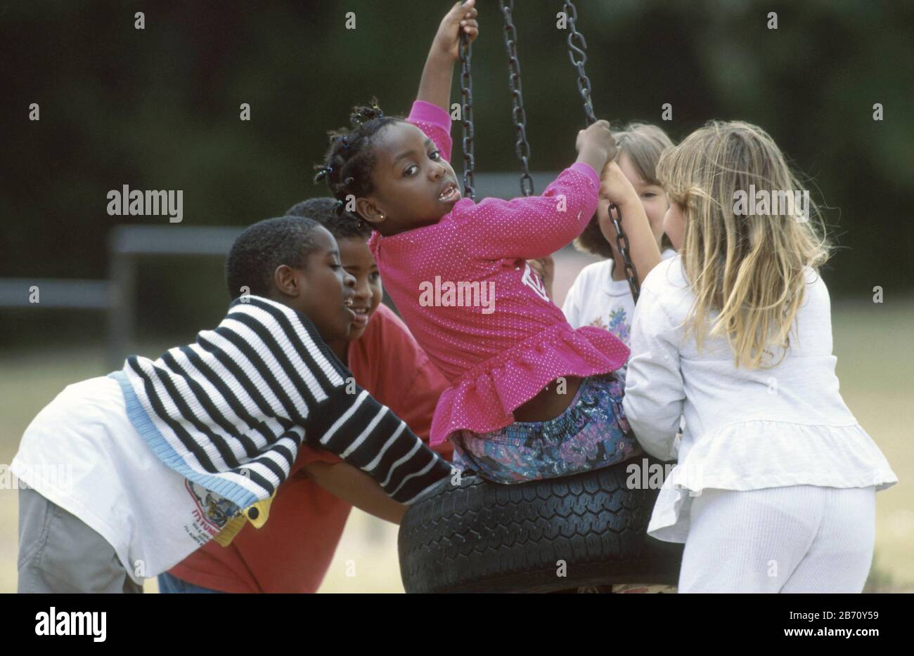 Austin, Texas: Second- and third-grade students play on a tire swing on ...