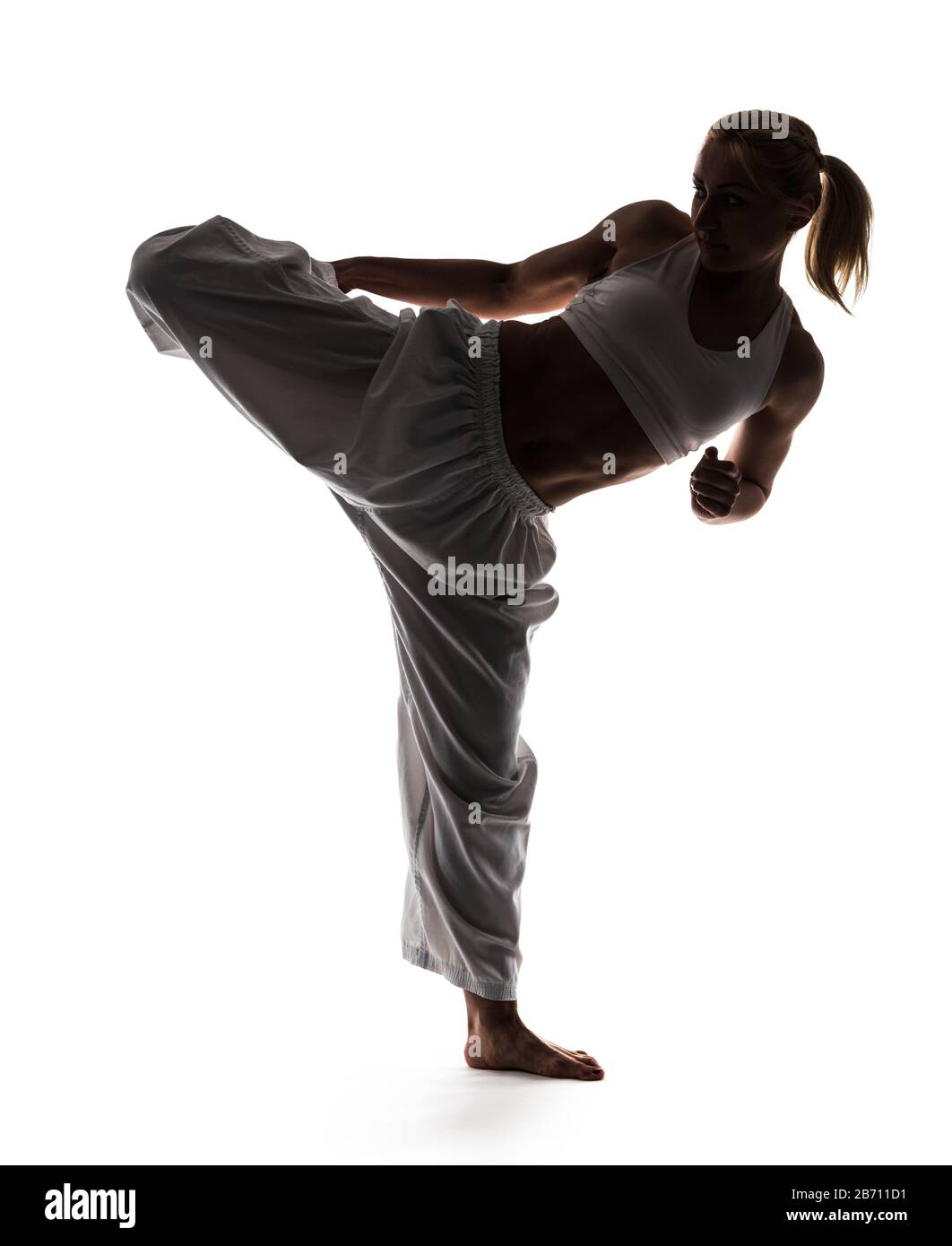 Karate woman dressed in kimono and poses while standing on one leg ...