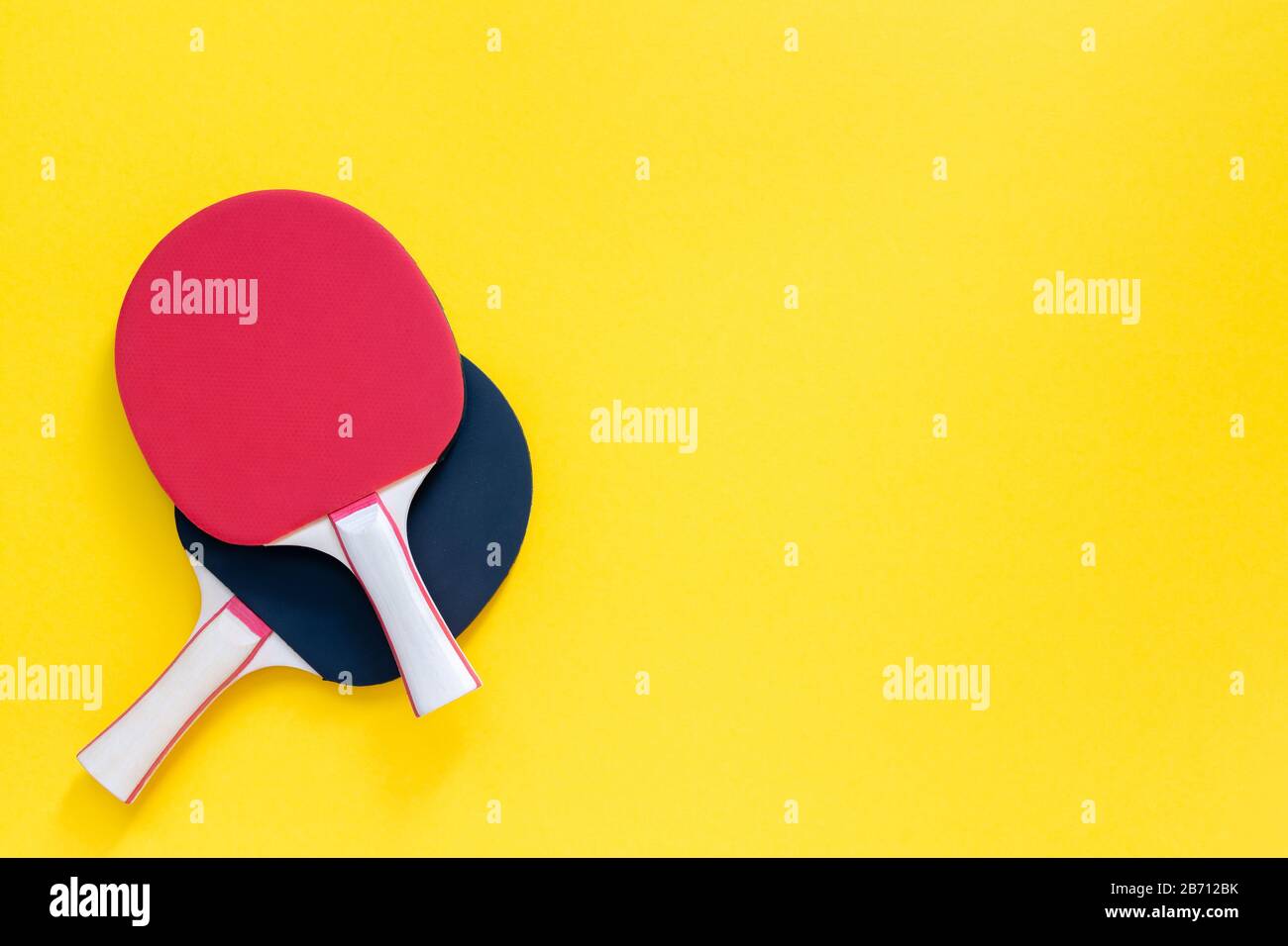 Red and black tennis ping pong rackets isolated on a yellow background ...