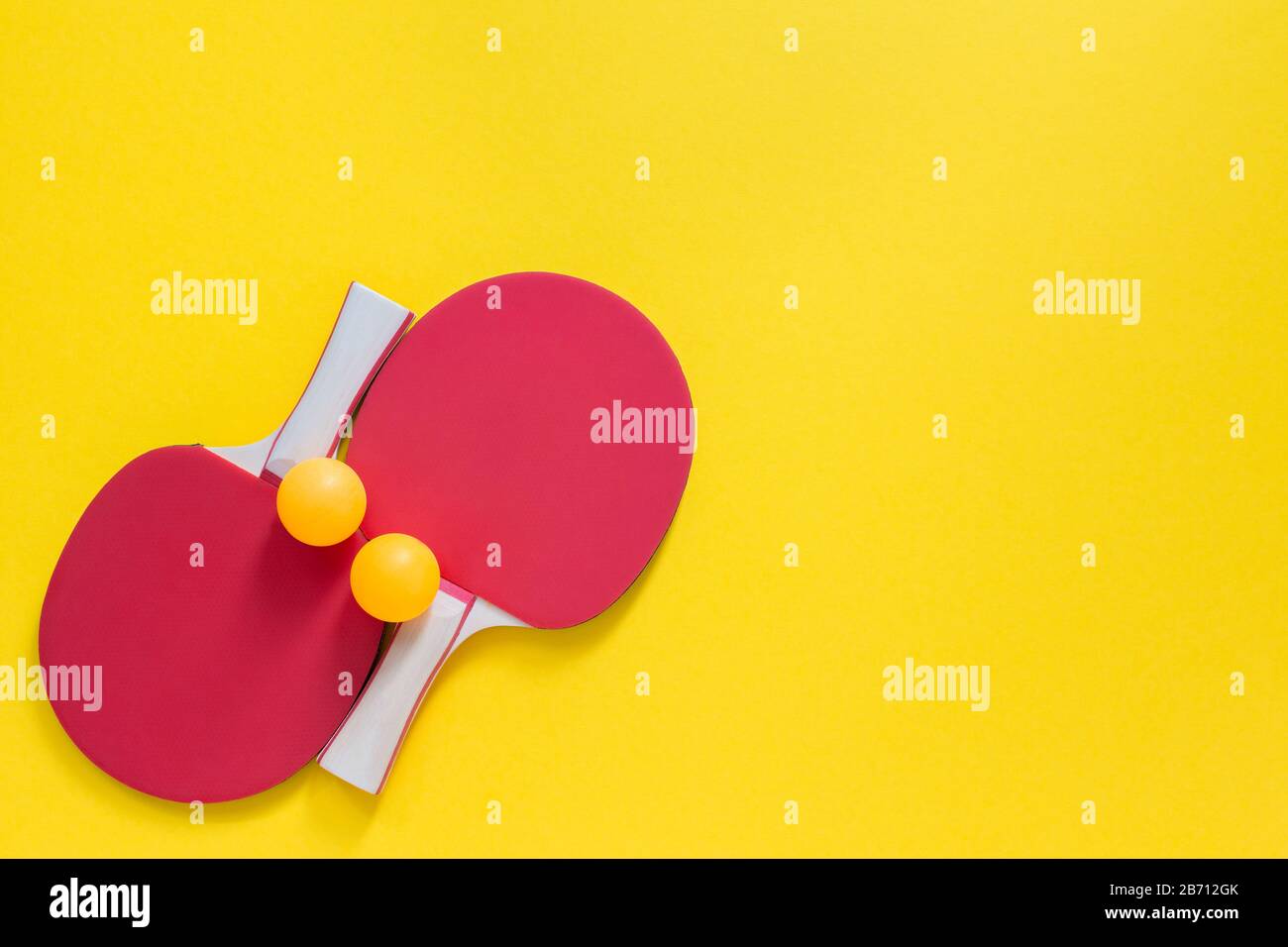 Red tennis ping pong rackets and orange balls isolated on a yellow ...