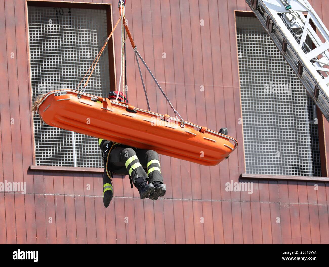 suspended firefighter with stretcher with people during practice in the ...