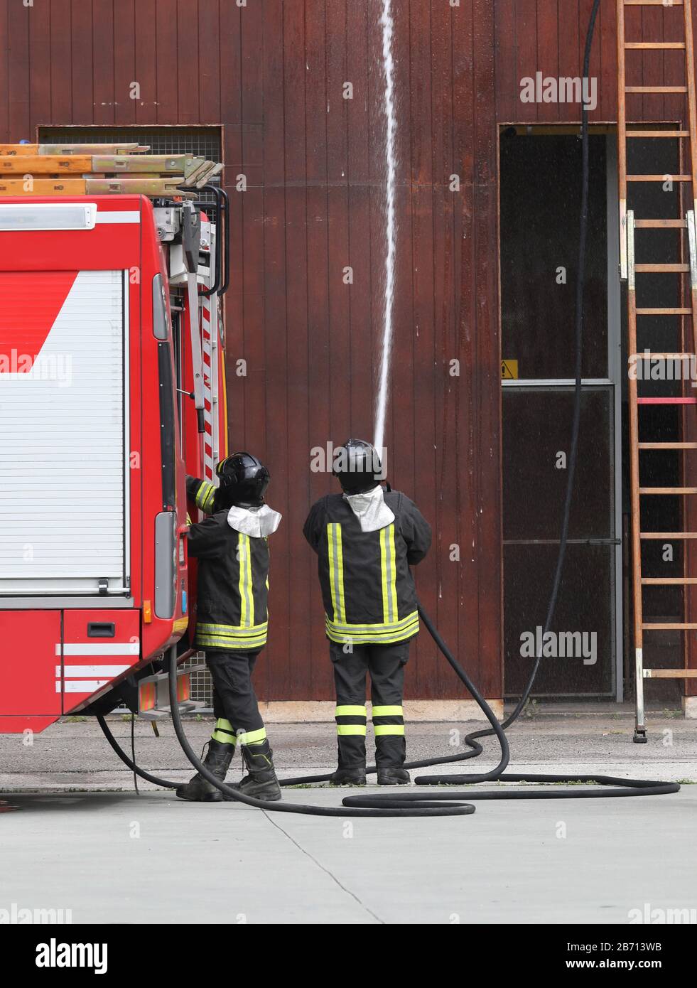 two firefighters engaged with a fire hydrant to put out the fire and ...