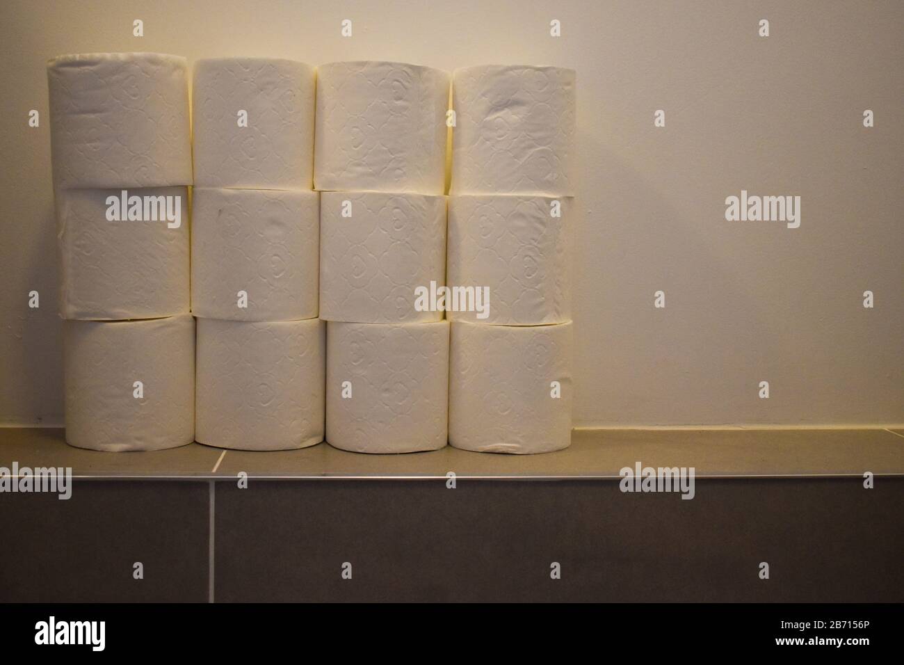 A close up of a pile of toilet paper rolls stacked in a bathroom ...