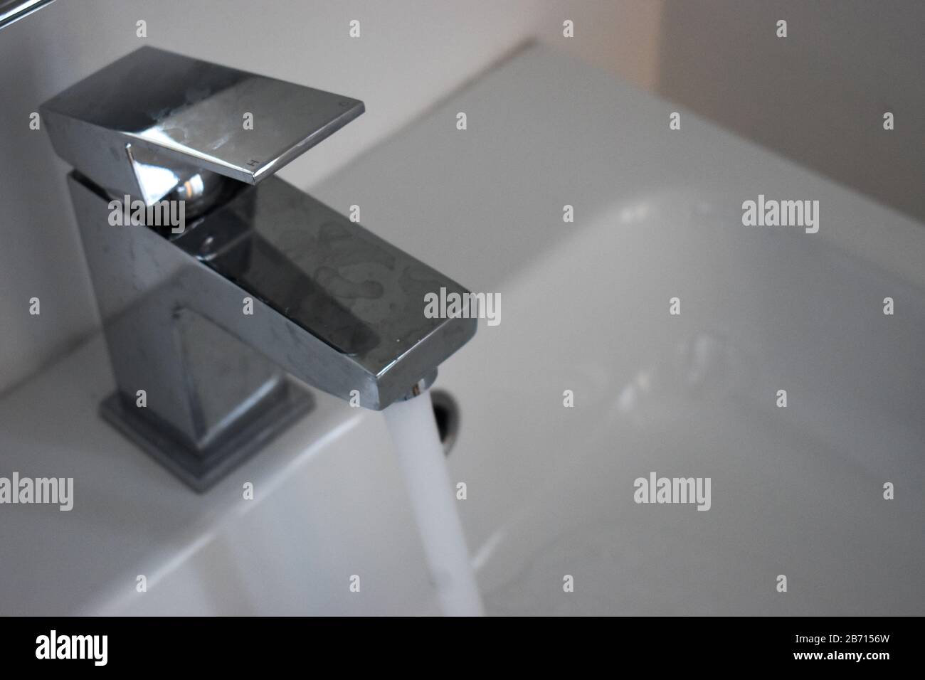 A close up of a bathroom tap with running water. Concept for washing ...