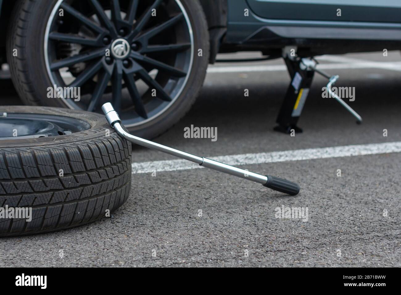 A flat tire car wheel and screwdriver are on a asphalt road on the ...
