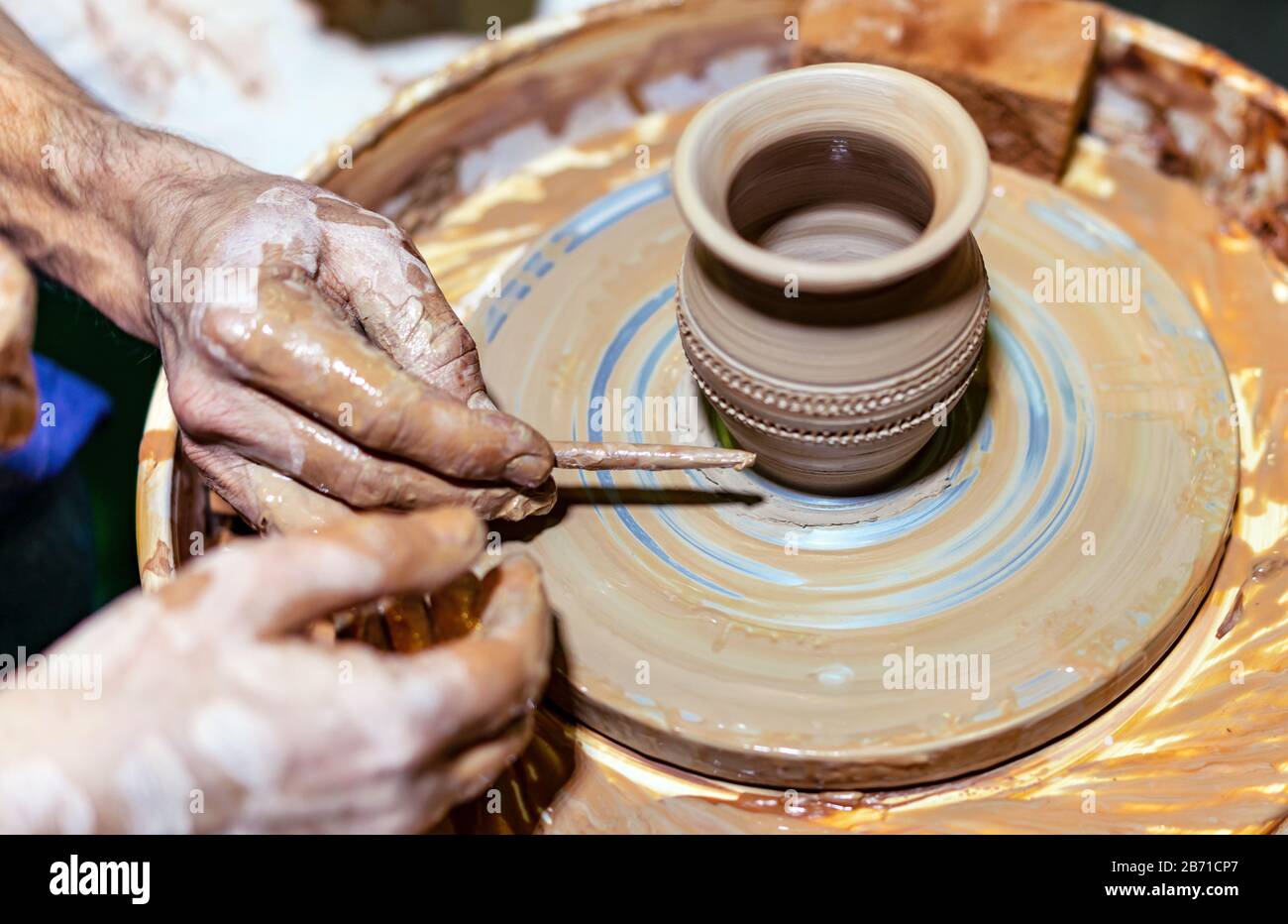 Professional potter makes a pot on a pottery wheel and teaches a pupil ...