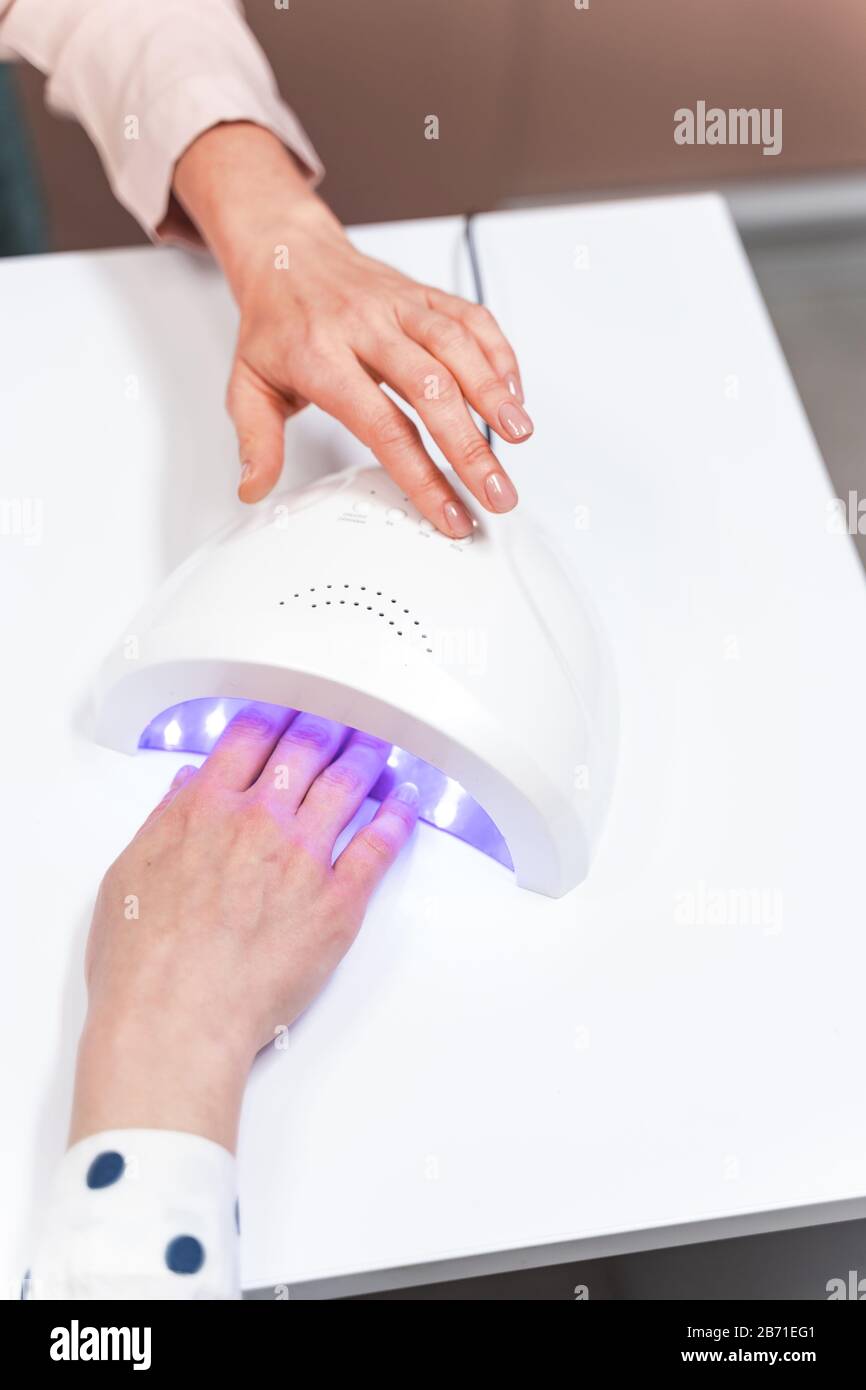 Competent manicure master turning on timer on lamp Stock Photo - Alamy
