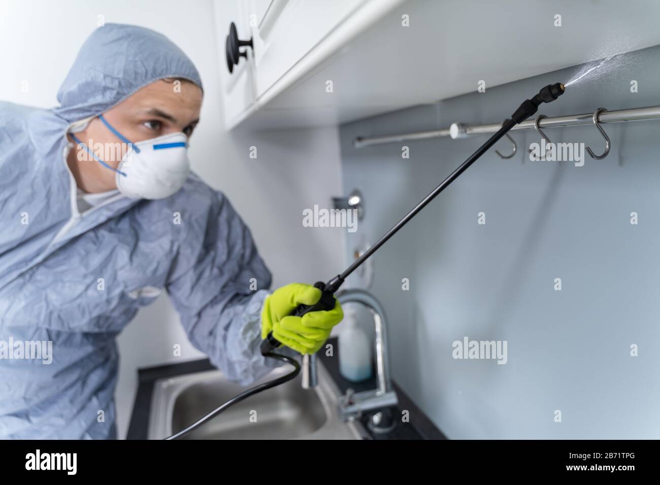 Side View Of Exterminator In Workwear Spraying Pesticide In Kitchen ...