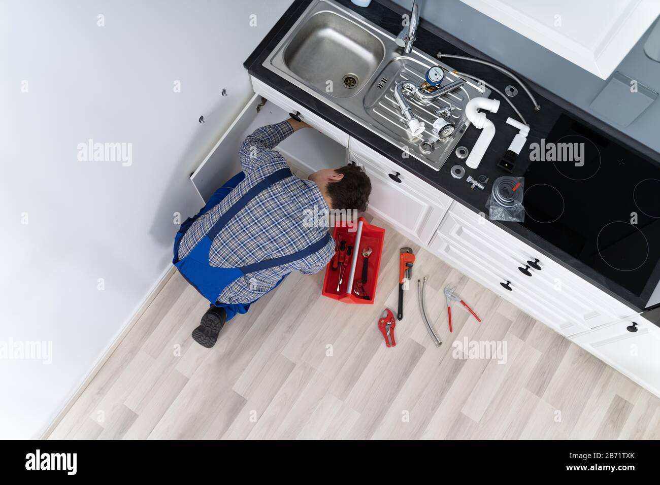 Worker Lying On Floor Repairing Kitchen Sink With Adjustable Wrench ...