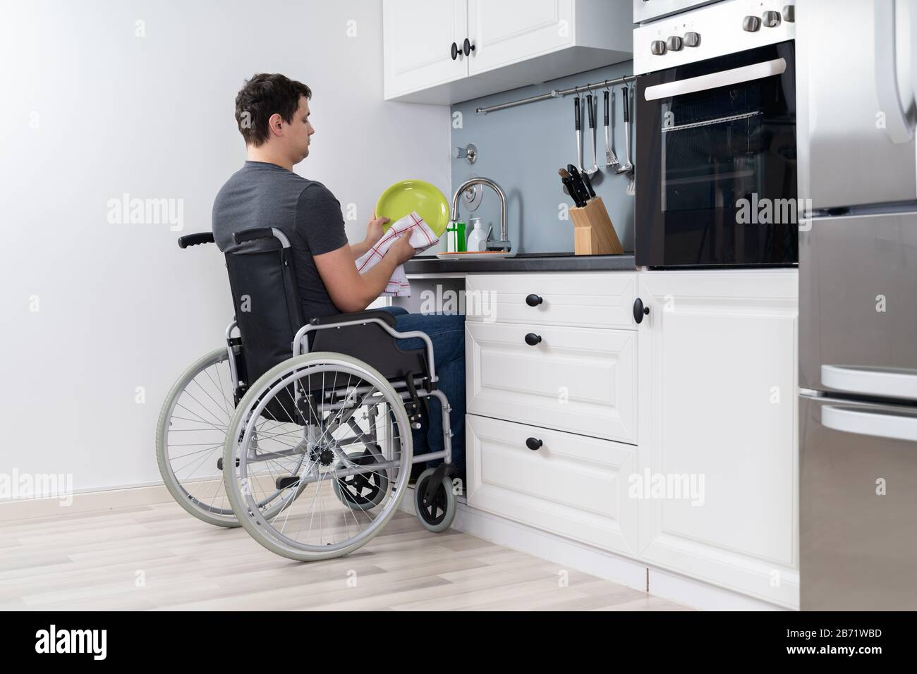Handicapped Man Sitting On Wheelchair Washing And Cleaning Dishes In ...