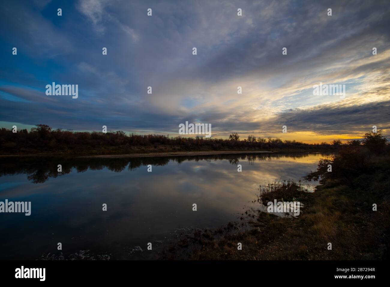sunset reflecting in the calm waters of the South Saskatchewan River ...