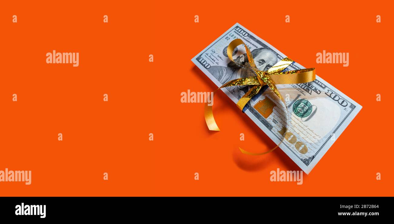 Stack of dollar banknotes with golden bow on orange background. Banner ...
