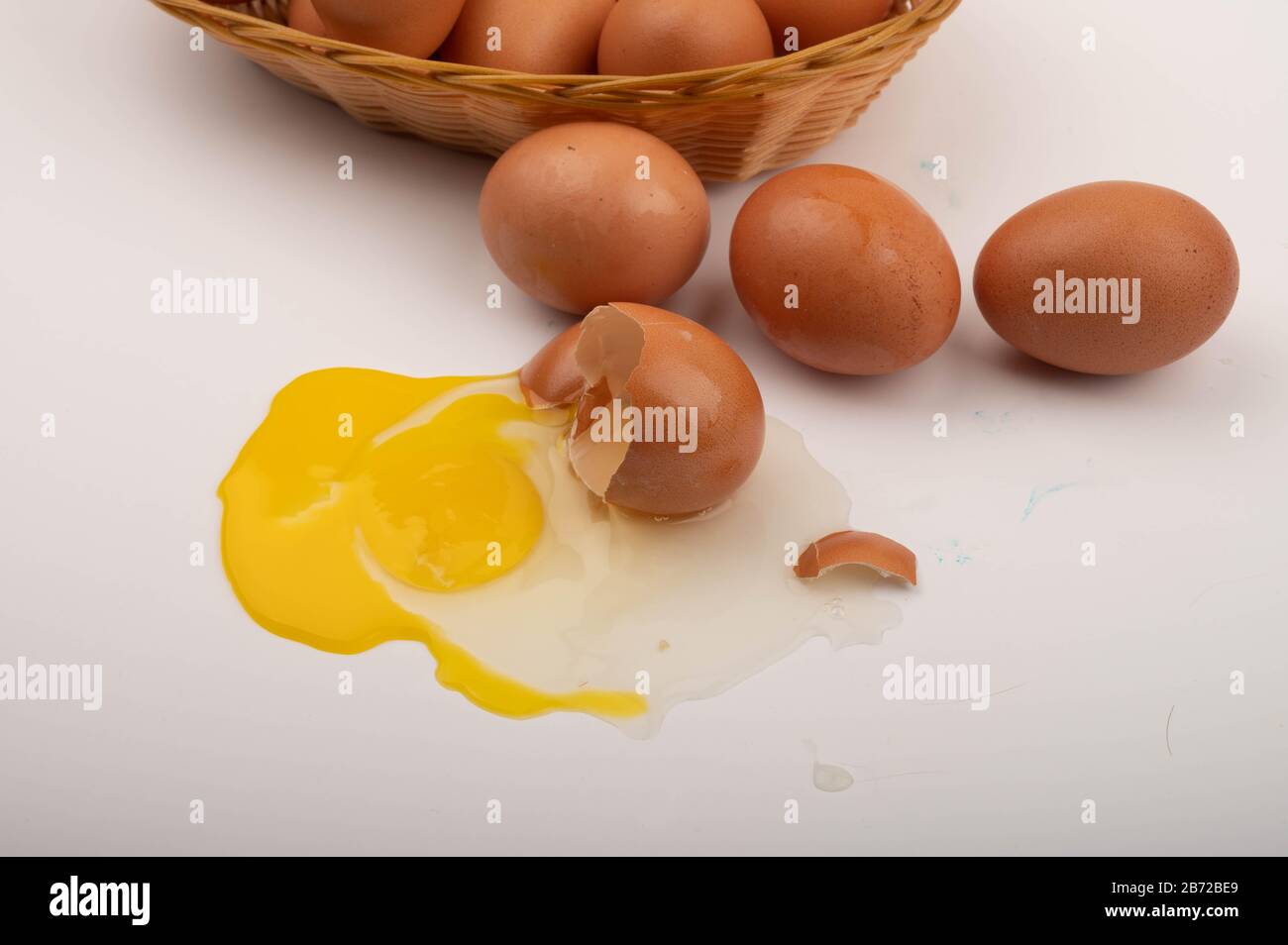 A broken chicken egg and scattered eggs on a white background. Close up ...