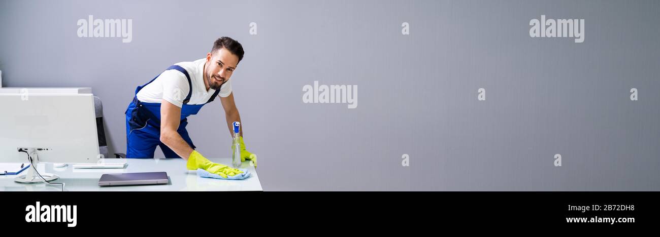 Worker Cleaning Computer Desk With Spray And Sponge Stock Photo - Alamy