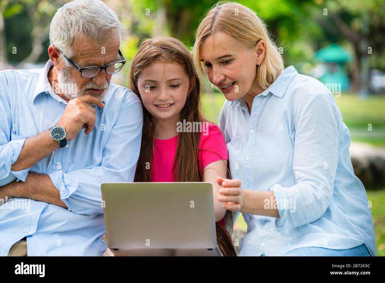 Happy family using laptop computer together in the garden park in ...