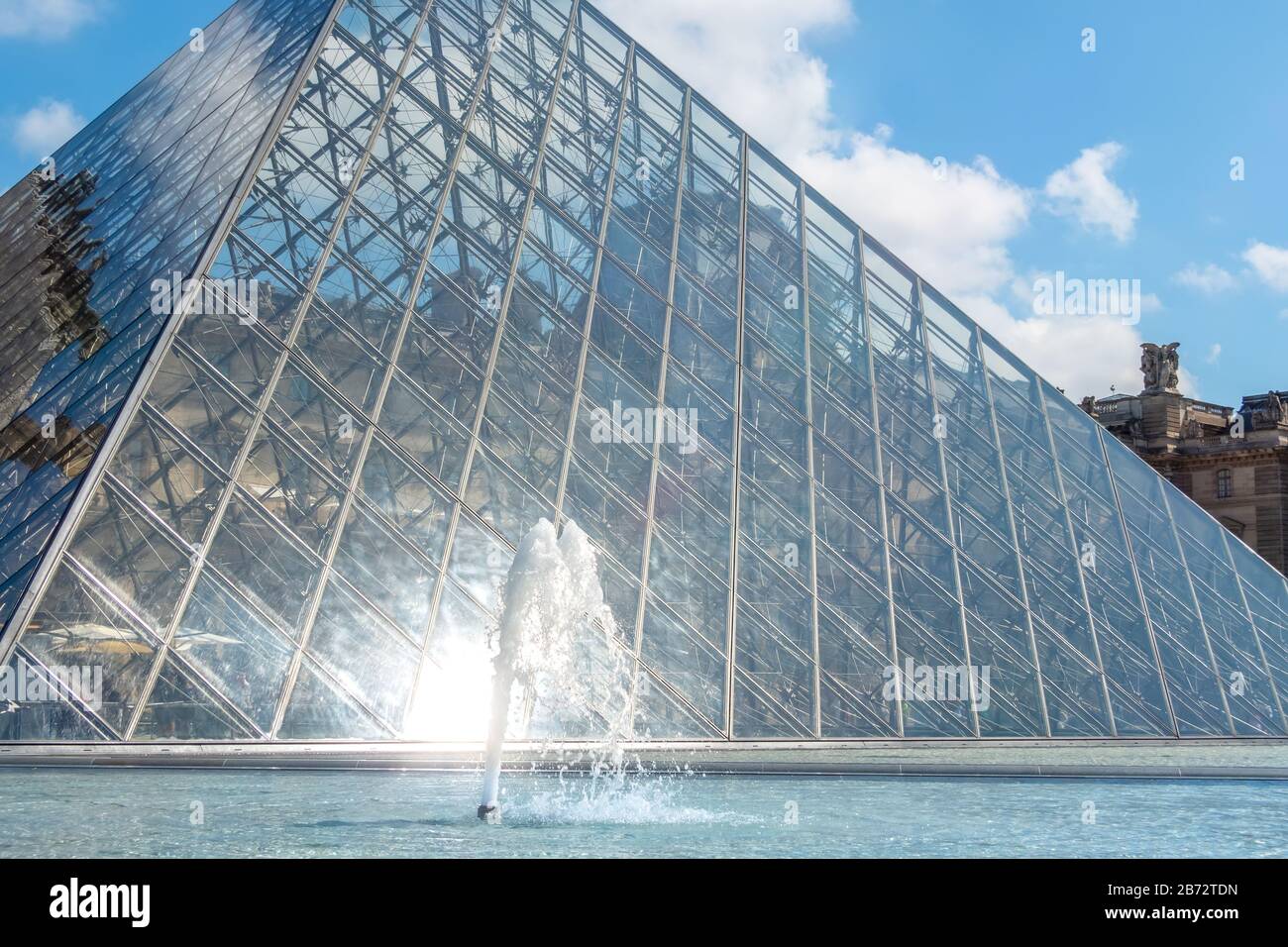 France. Sunny day in Paris. Glass pyramid and fountain in the courtyard ...