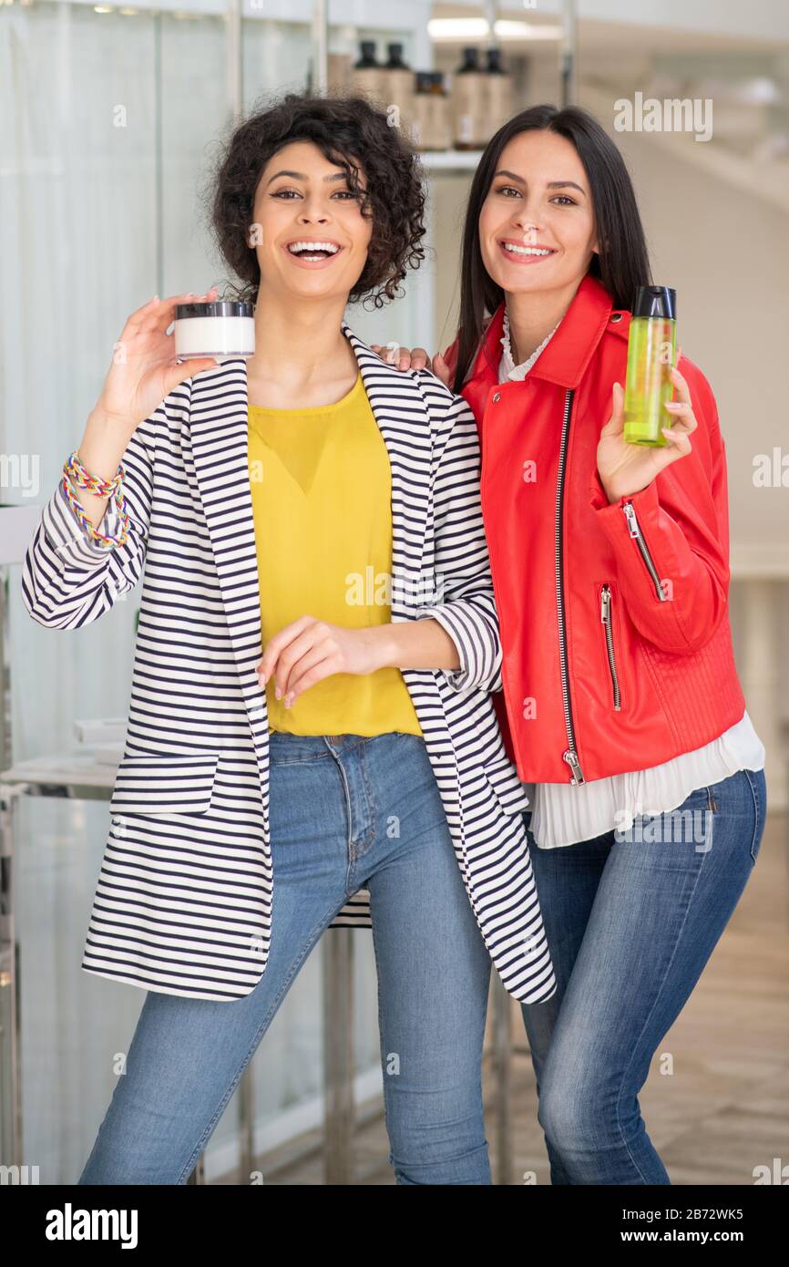 Two good-looking dark-haired girls showing body care products Stock ...