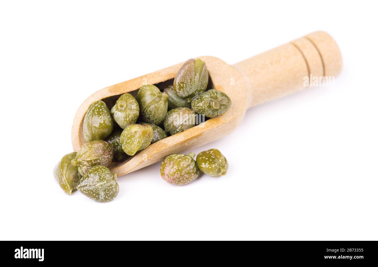 Capers in a wooden spoon, isolated on white background. Pickled capers ...