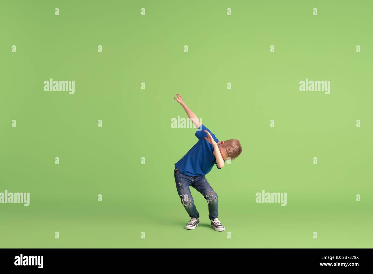 Dabbing. Happy boy playing and having fun on green studio background ...