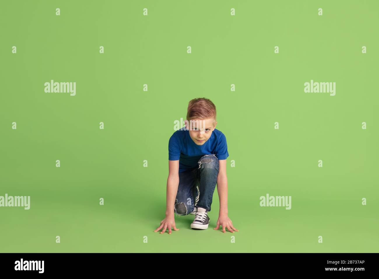 Starting. Happy boy playing and having fun on green studio background ...