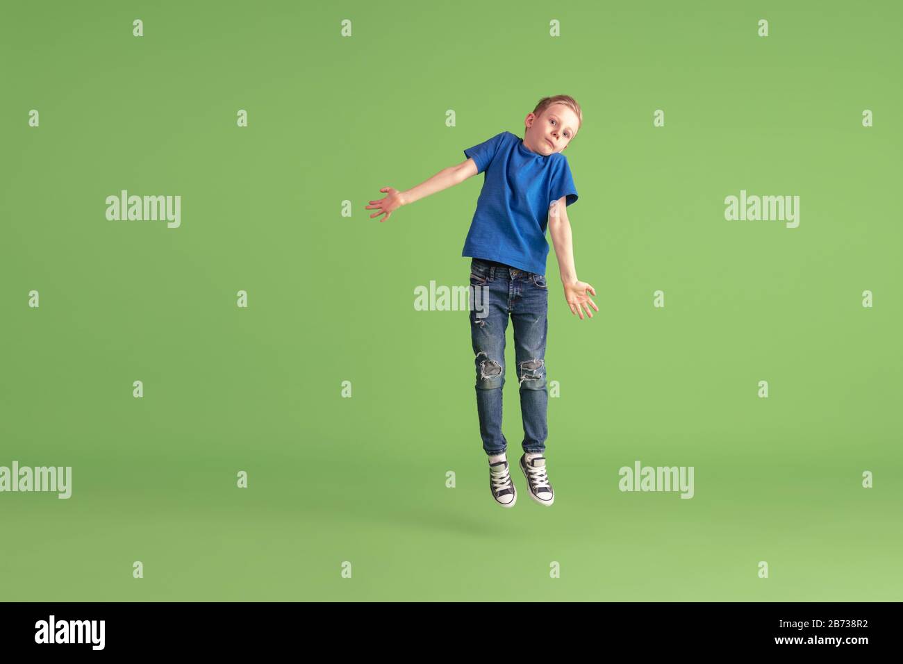 Uncertain. Happy boy playing and having fun on green studio background ...