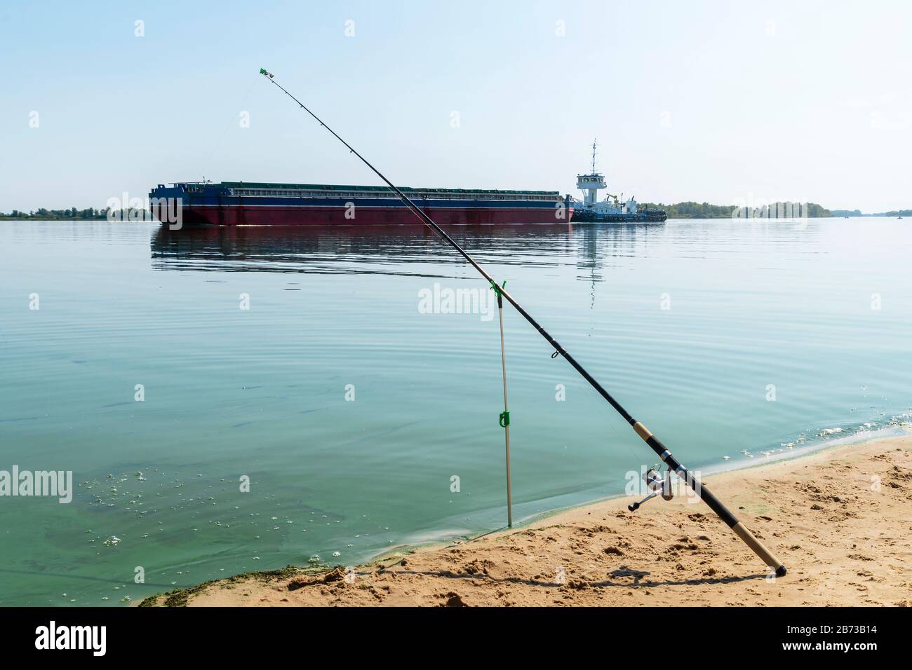 Fishing rod against tanker barge with grain on the Ukraine Dniepr river ...