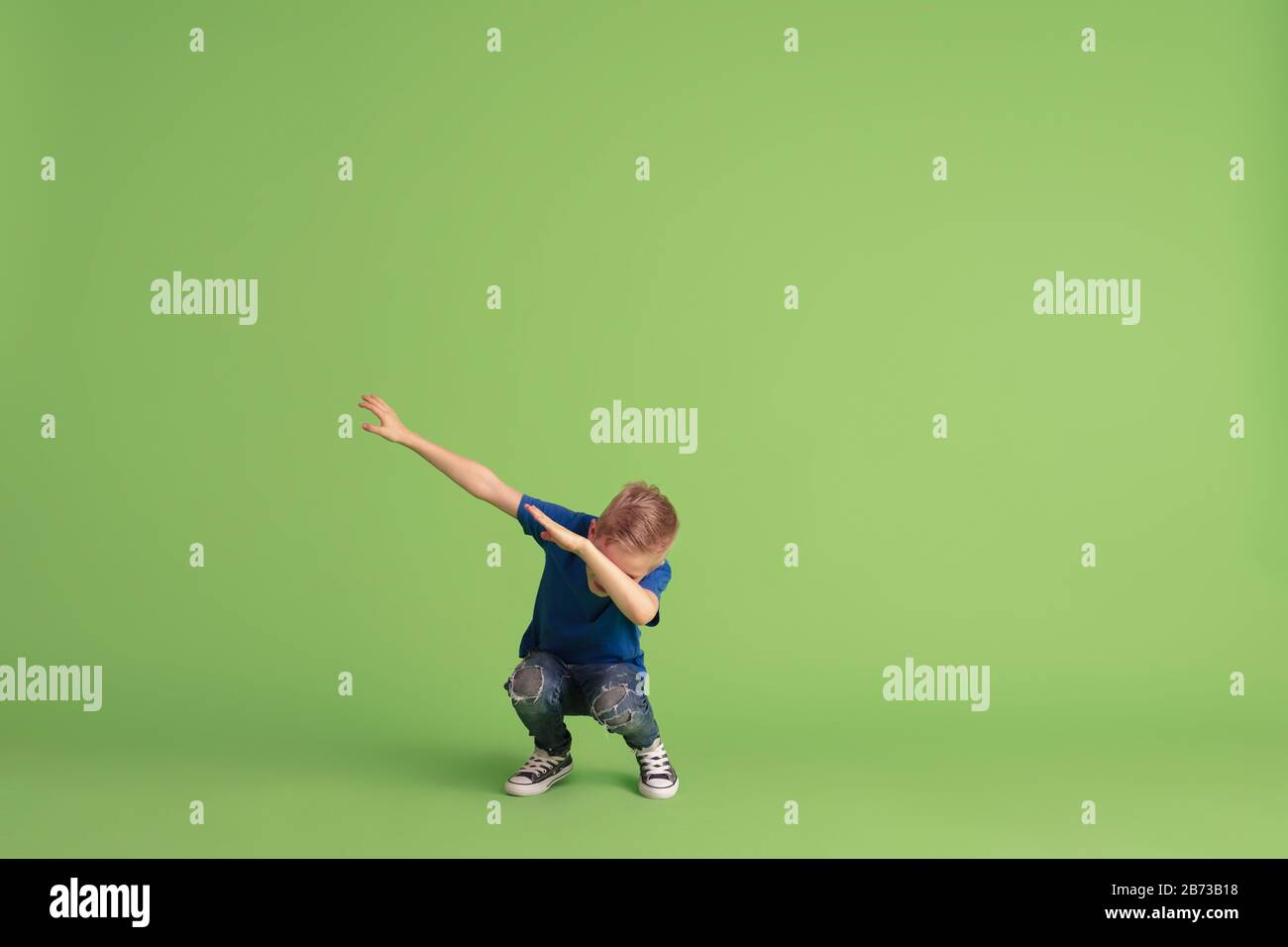 Dabbing. Happy boy playing and having fun on green studio background ...