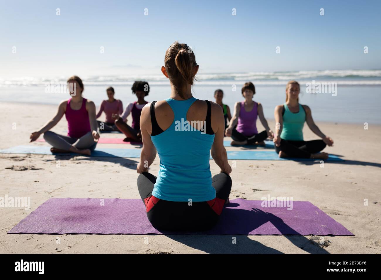 Rear view of yoga teacher doing a yoga session at the beach Stock Photo ...