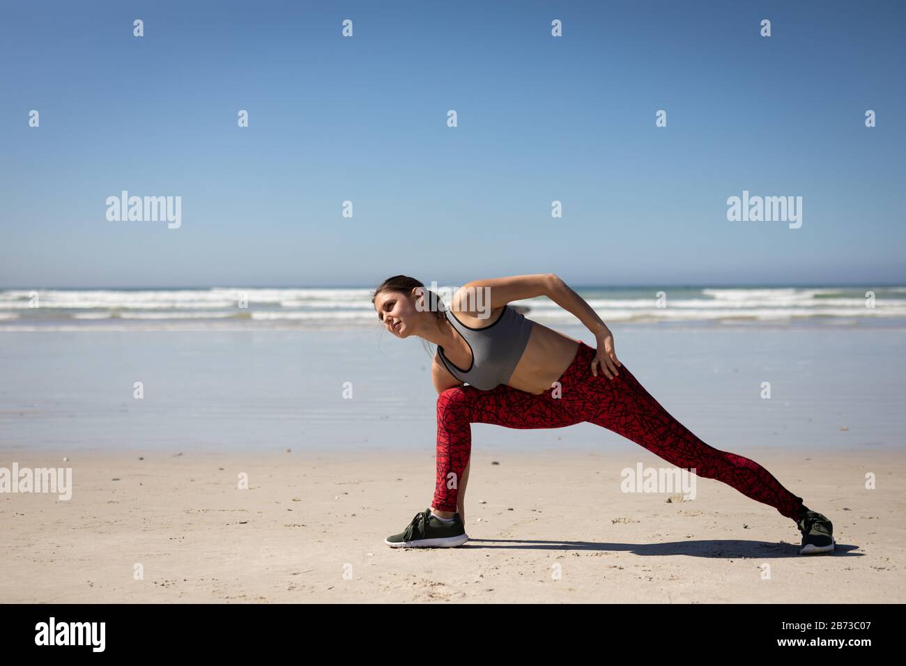 Side view of woman stretching at the beach Stock Photo - Alamy