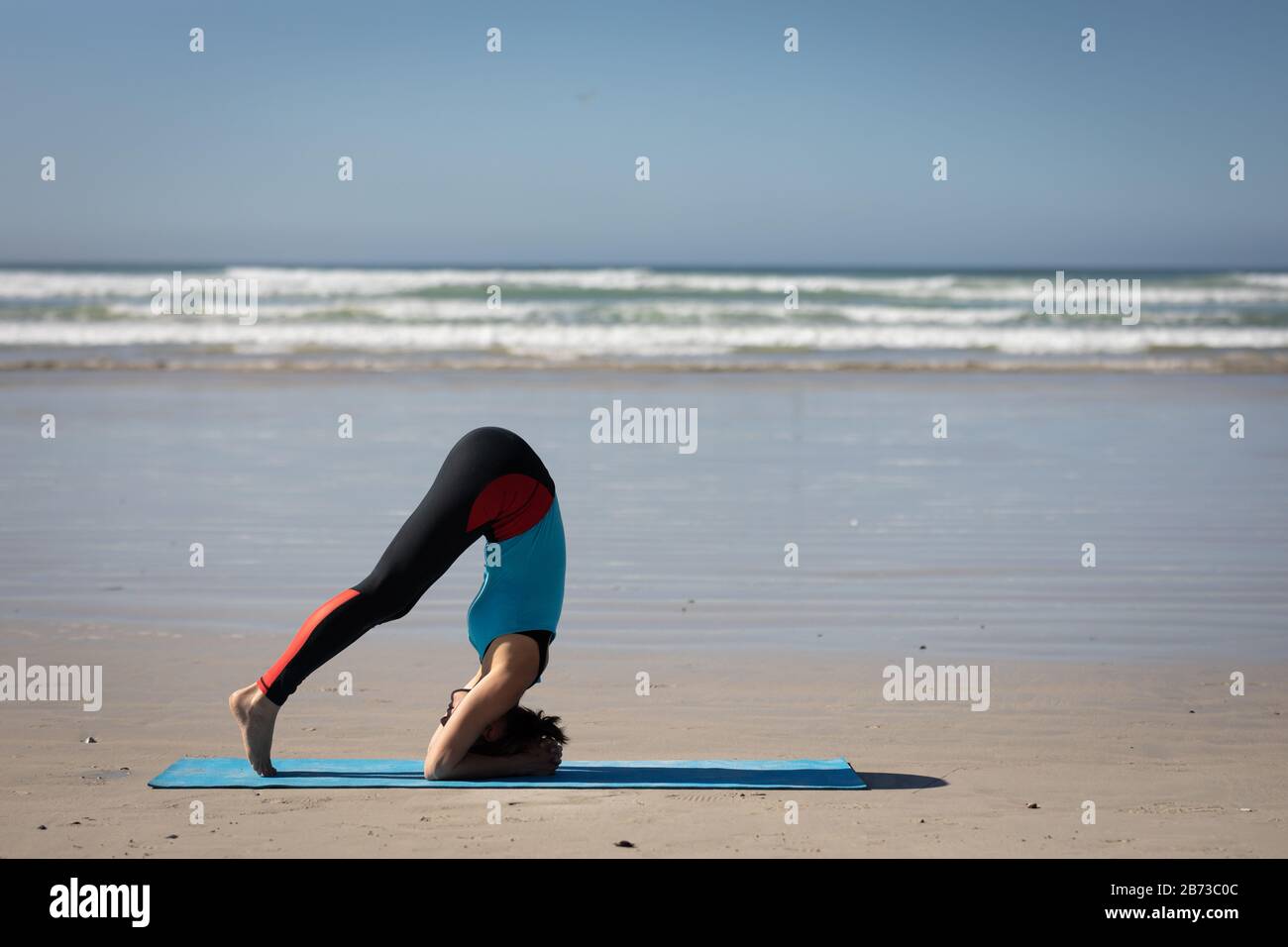 Side view of women doing yoga positions at the beach Stock Photo - Alamy