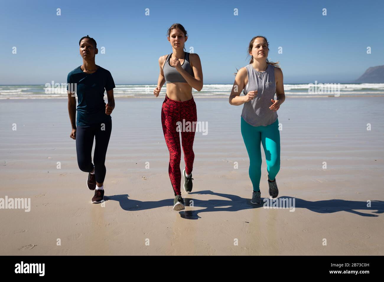 Front view of woman running together at the beach Stock Photo - Alamy