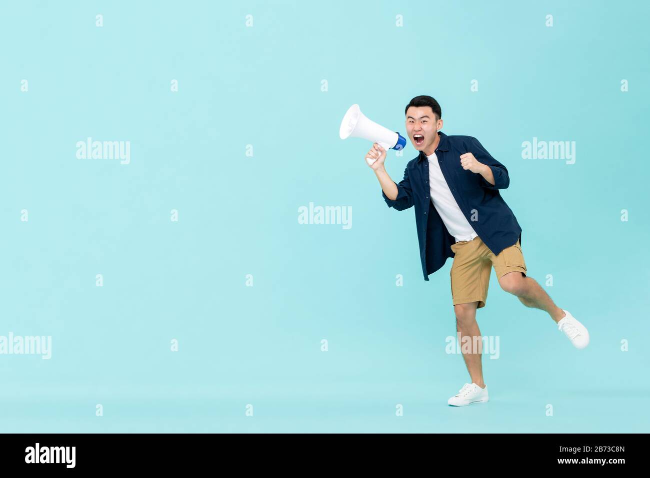 Excited young Asian man holding megaphone and shouting isolated on ...