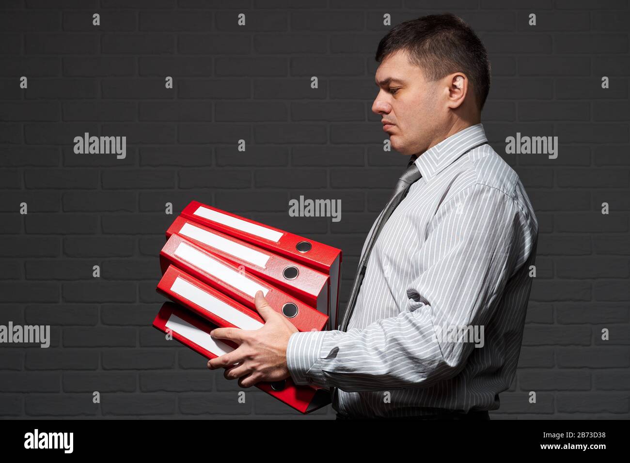 Very busy businessman closeup portrait, posing with red folders ...