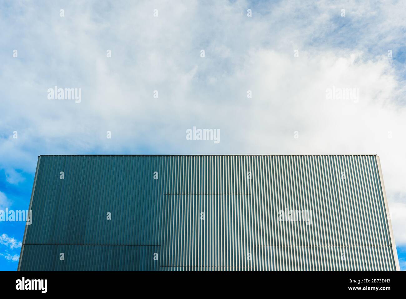 Aluminum wall at the back of a smooth windowless building and blue sky ...