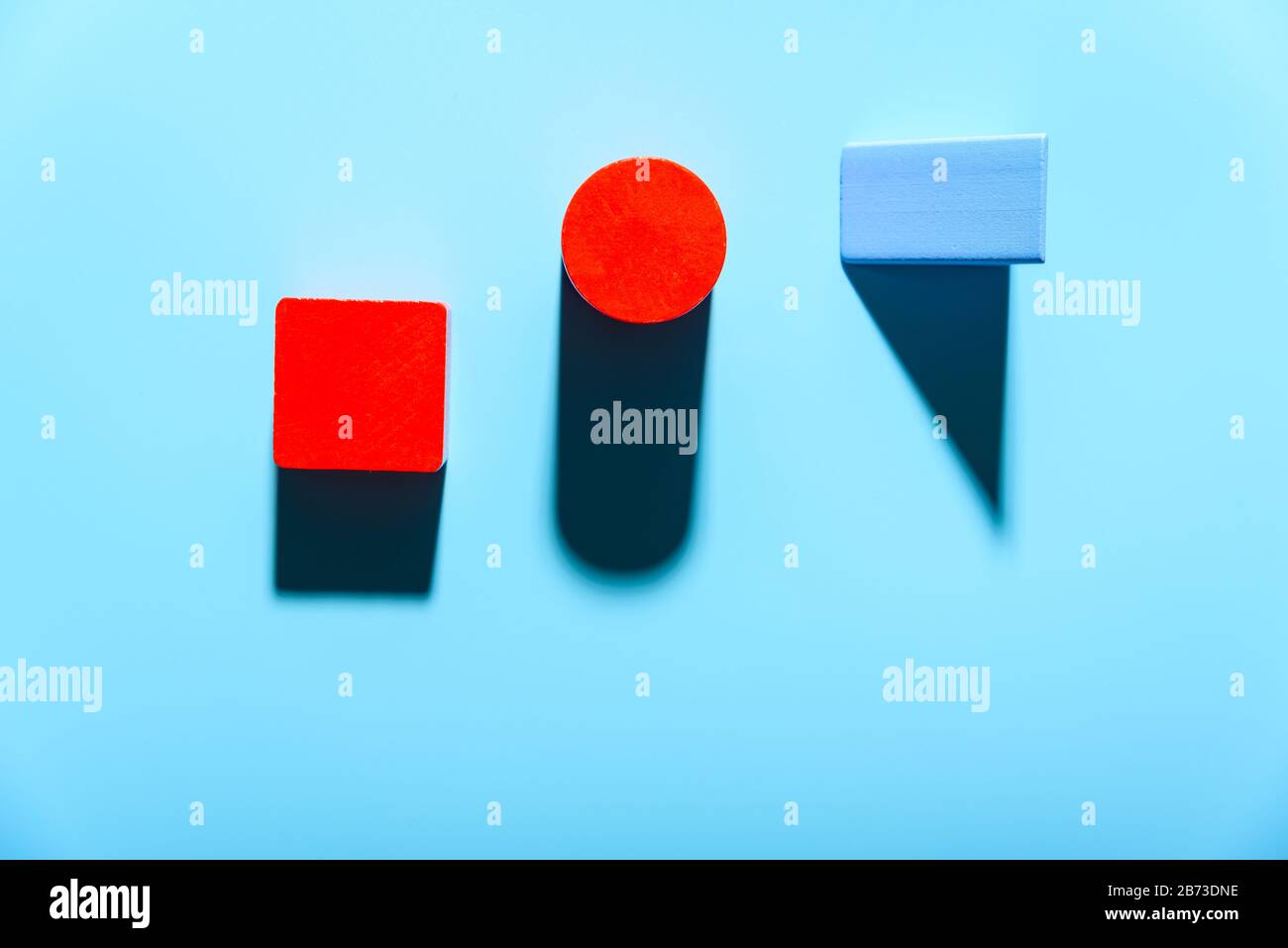 Three geometric figures of solid colors illuminated with hard light on ...