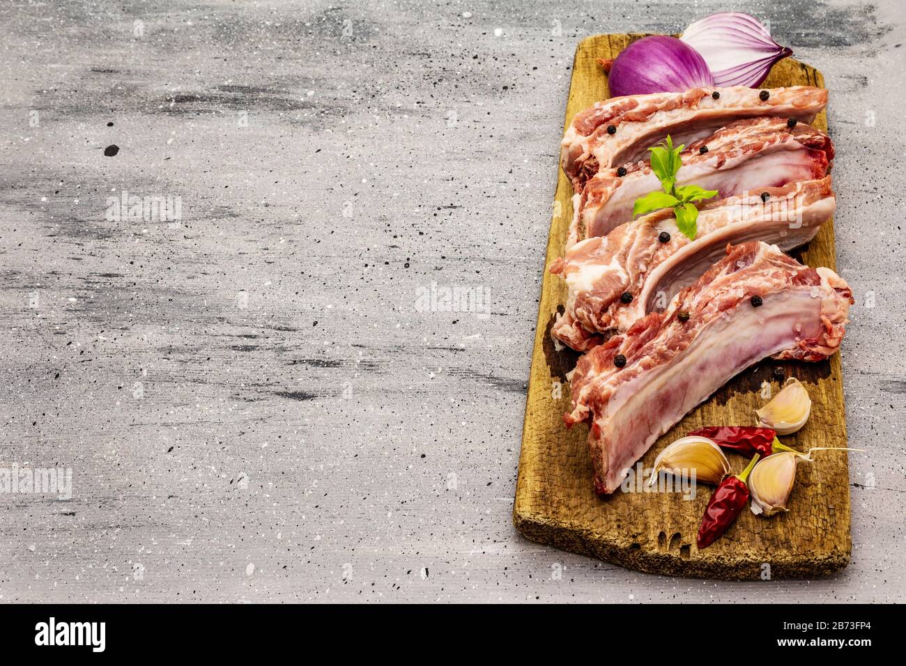Raw pork ribs on grey stone concrete background. Round wooden cutting ...