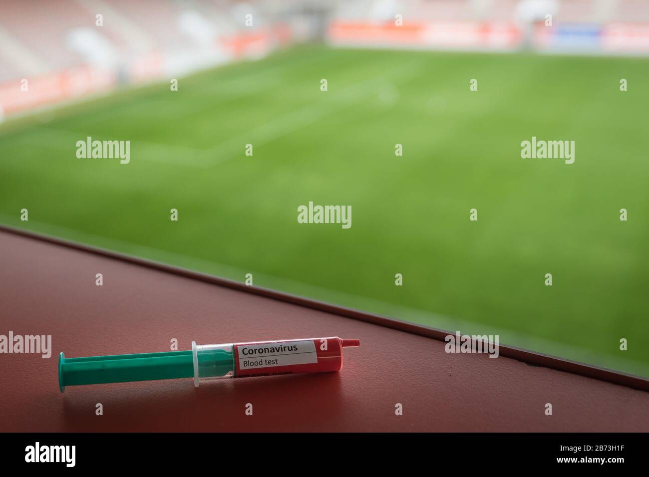 syringe with blood sample (coronavirus test) with football field in the ...
