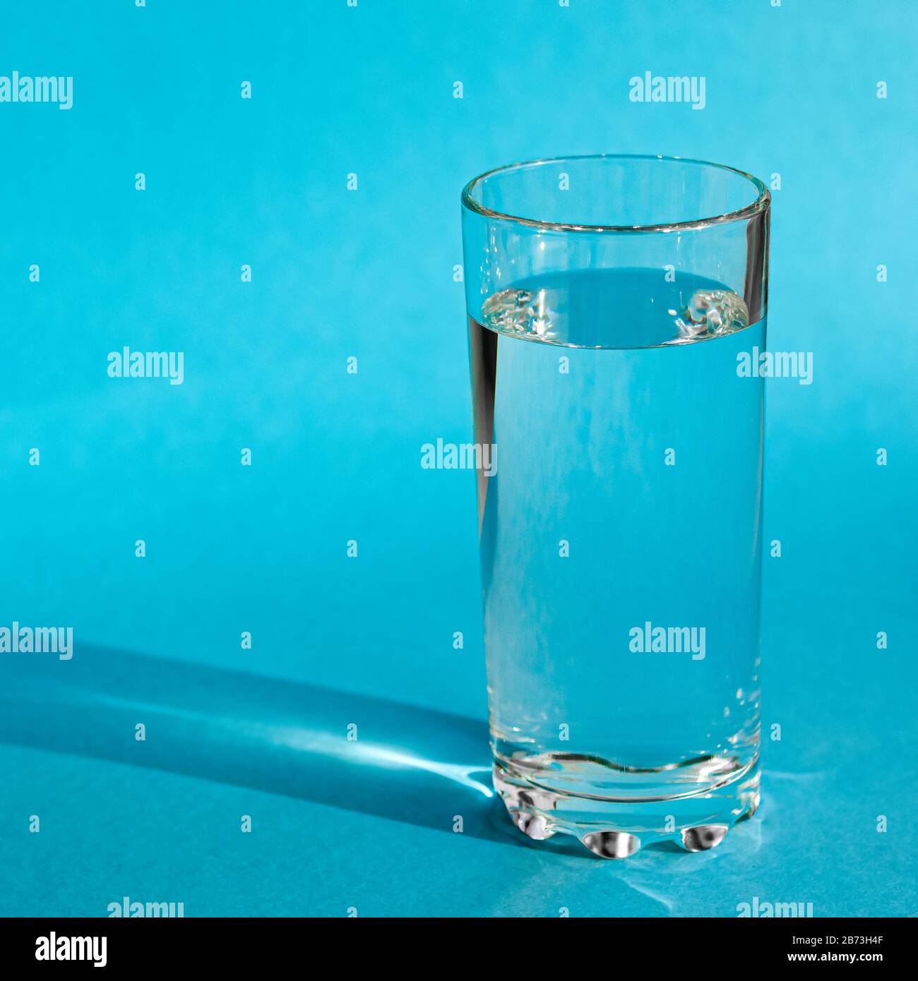 A glass with clean clear clear water stands on a blue background with ...