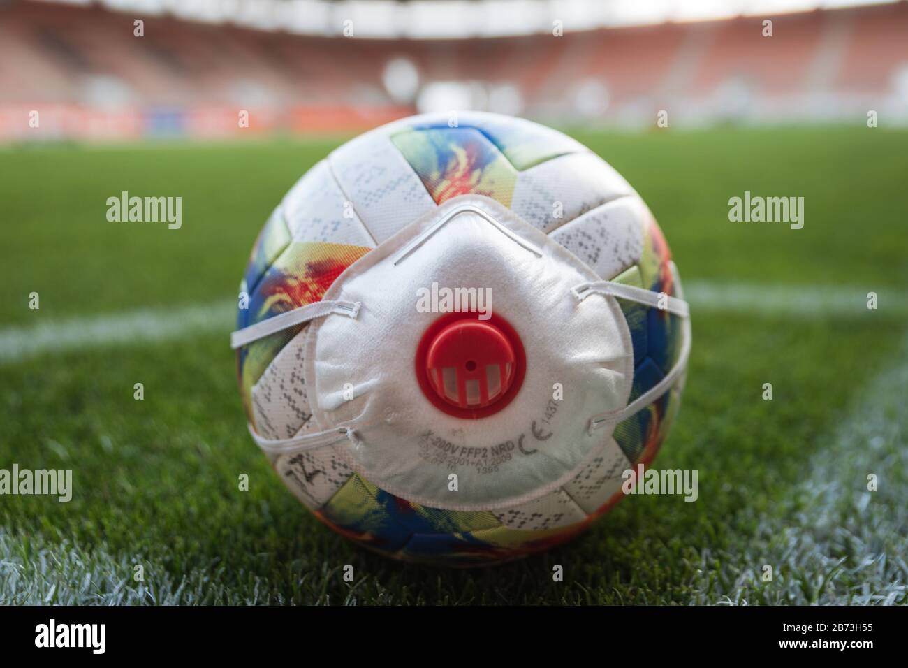 The ball with mask (symbol coronavirus) in the corner of soccer pitch ...