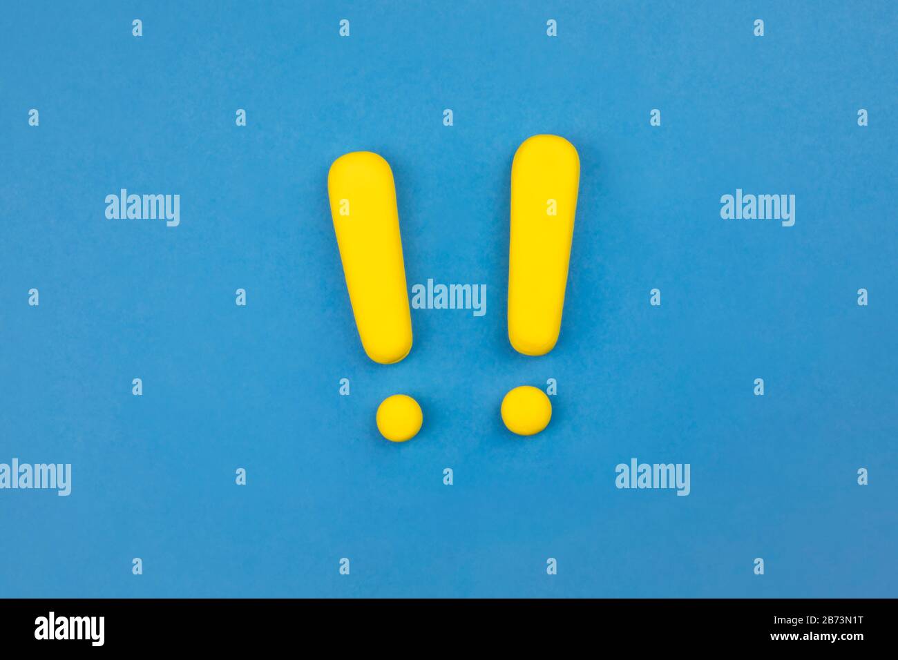 Two yellow vivid exclamation marks on blue background. Flat lay ...