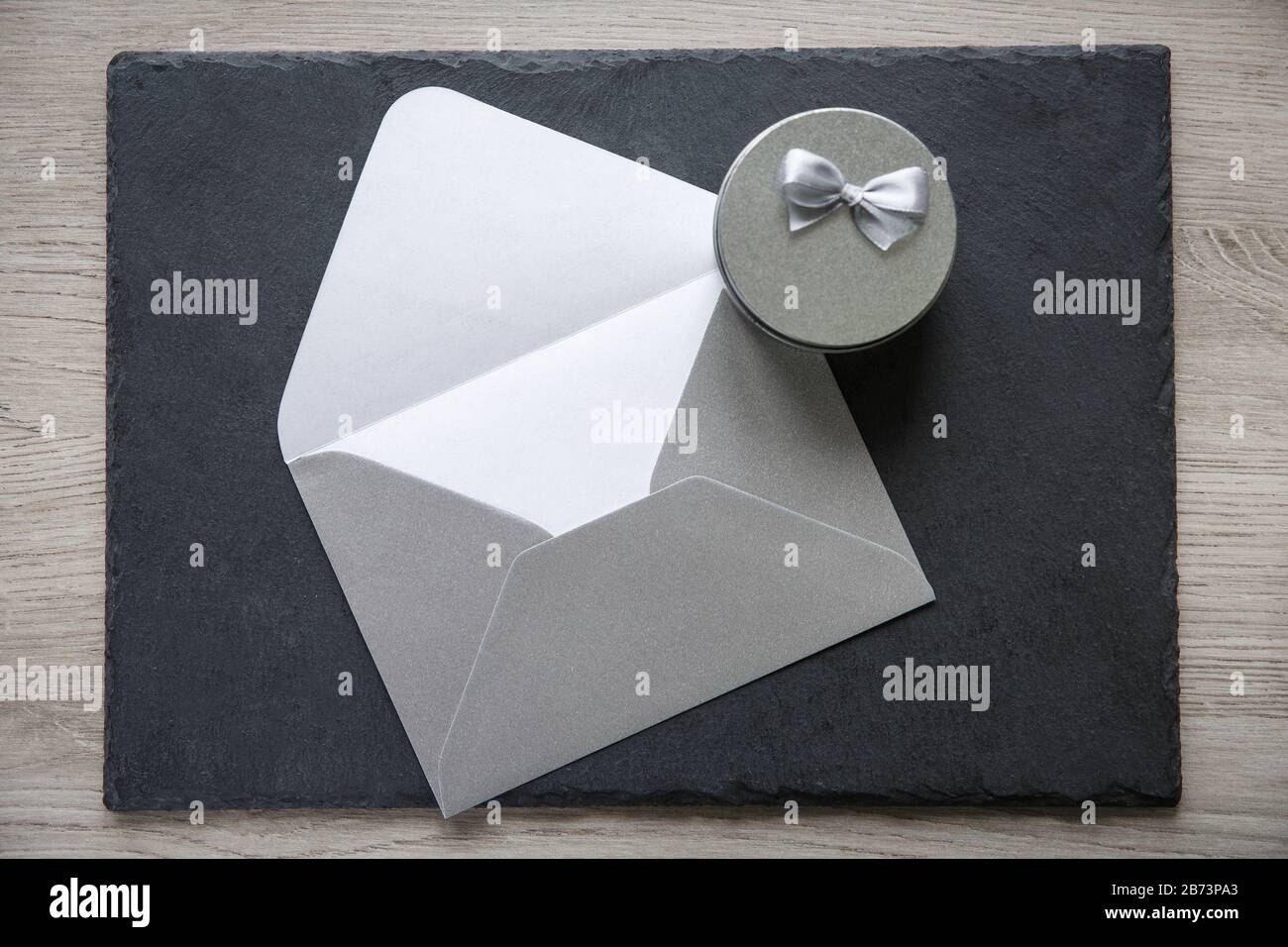 Letter envelope and small round silver gift box on black background ...