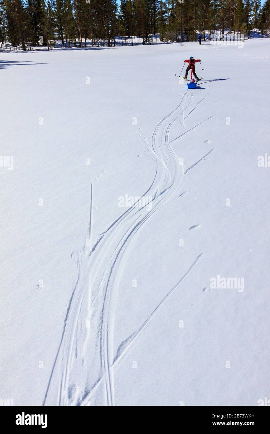 Swirly skiing tracks from young girl pulling her baby doll on a play ...