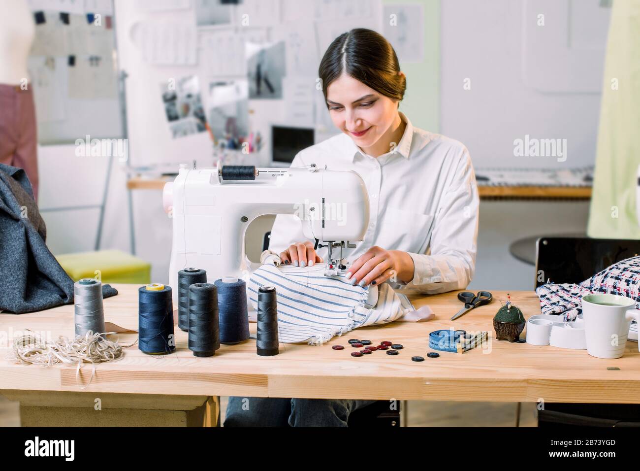 Beautiful seamstress sewing at her workshop. Dressmaker working on the ...