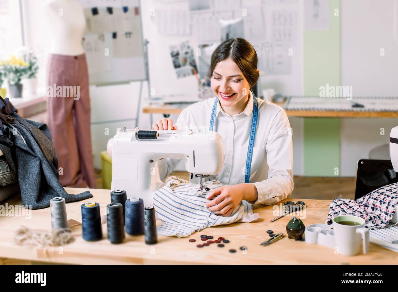 Closeup portrait of young woman seamstress sitting and sews on sewing ...