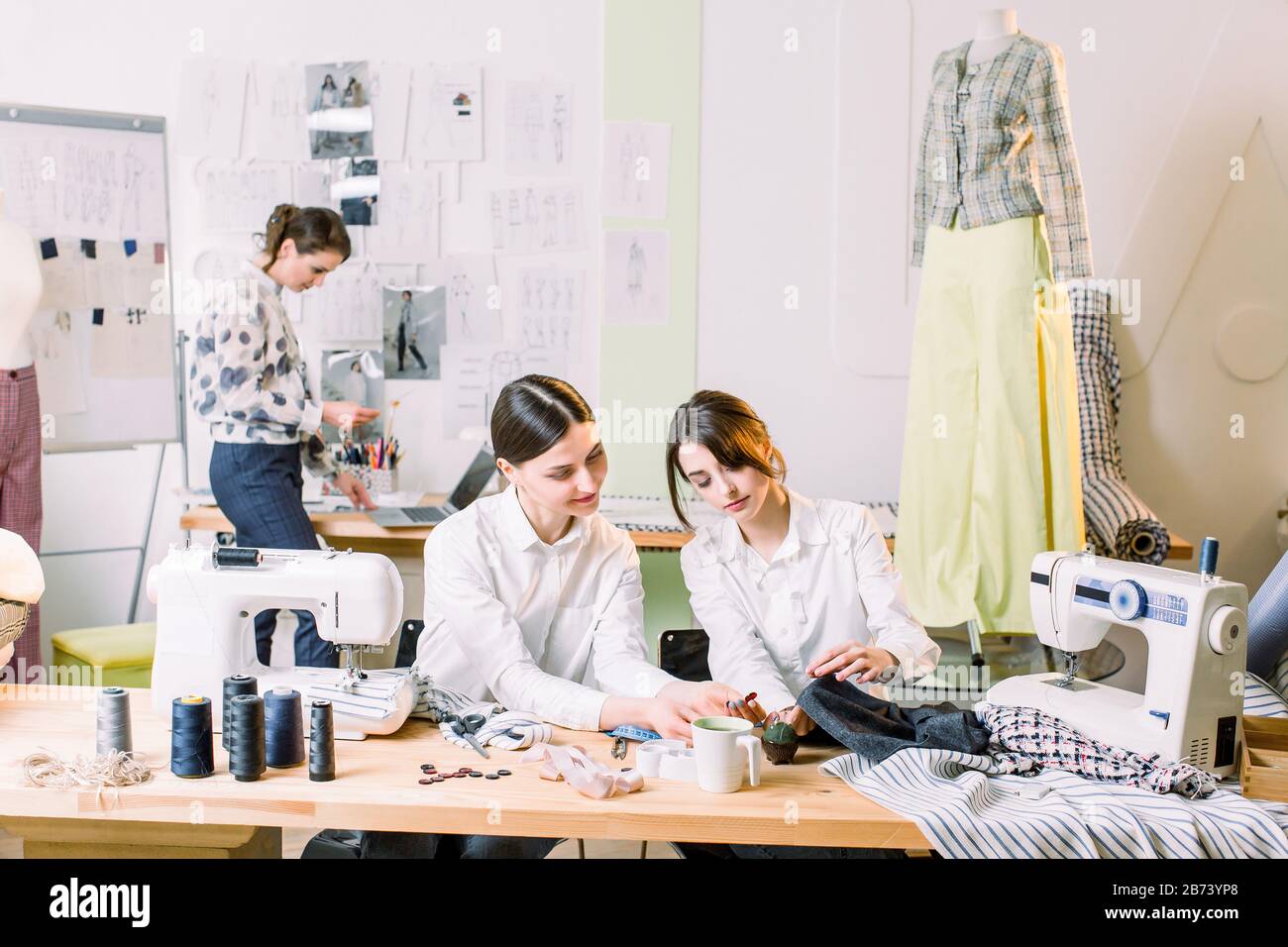 Fashion Design, dressmaker, tailor and fashion concept. Two young women ...