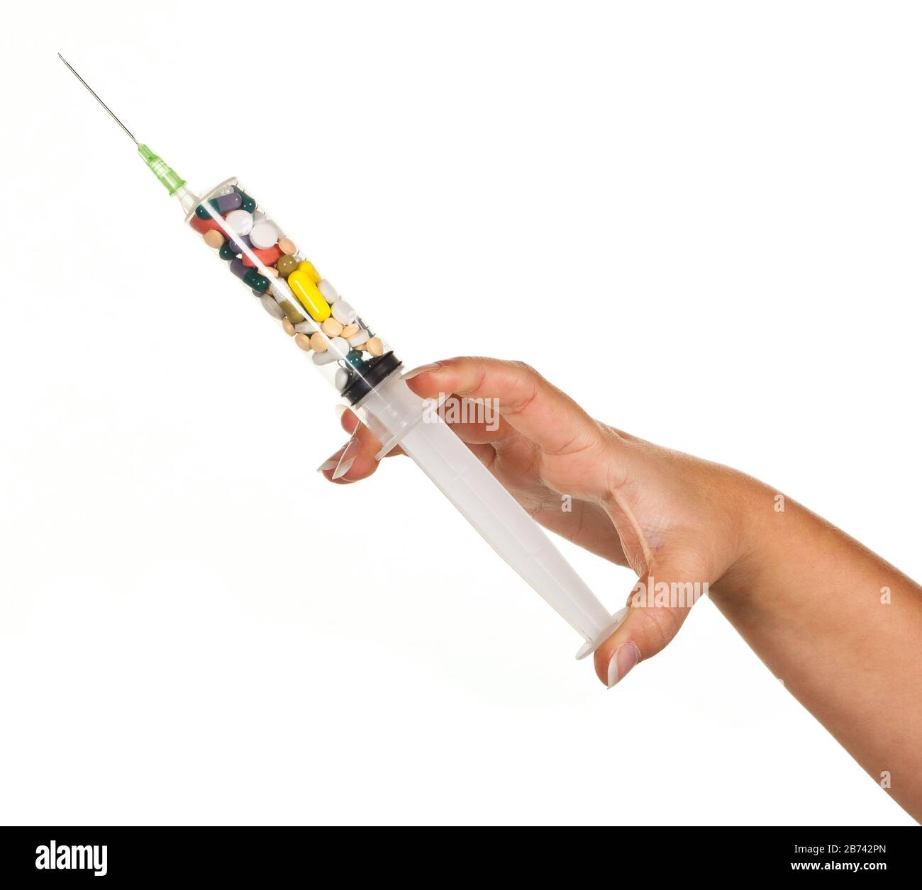 Hand holding a very large syringe filled with medication and pills ...