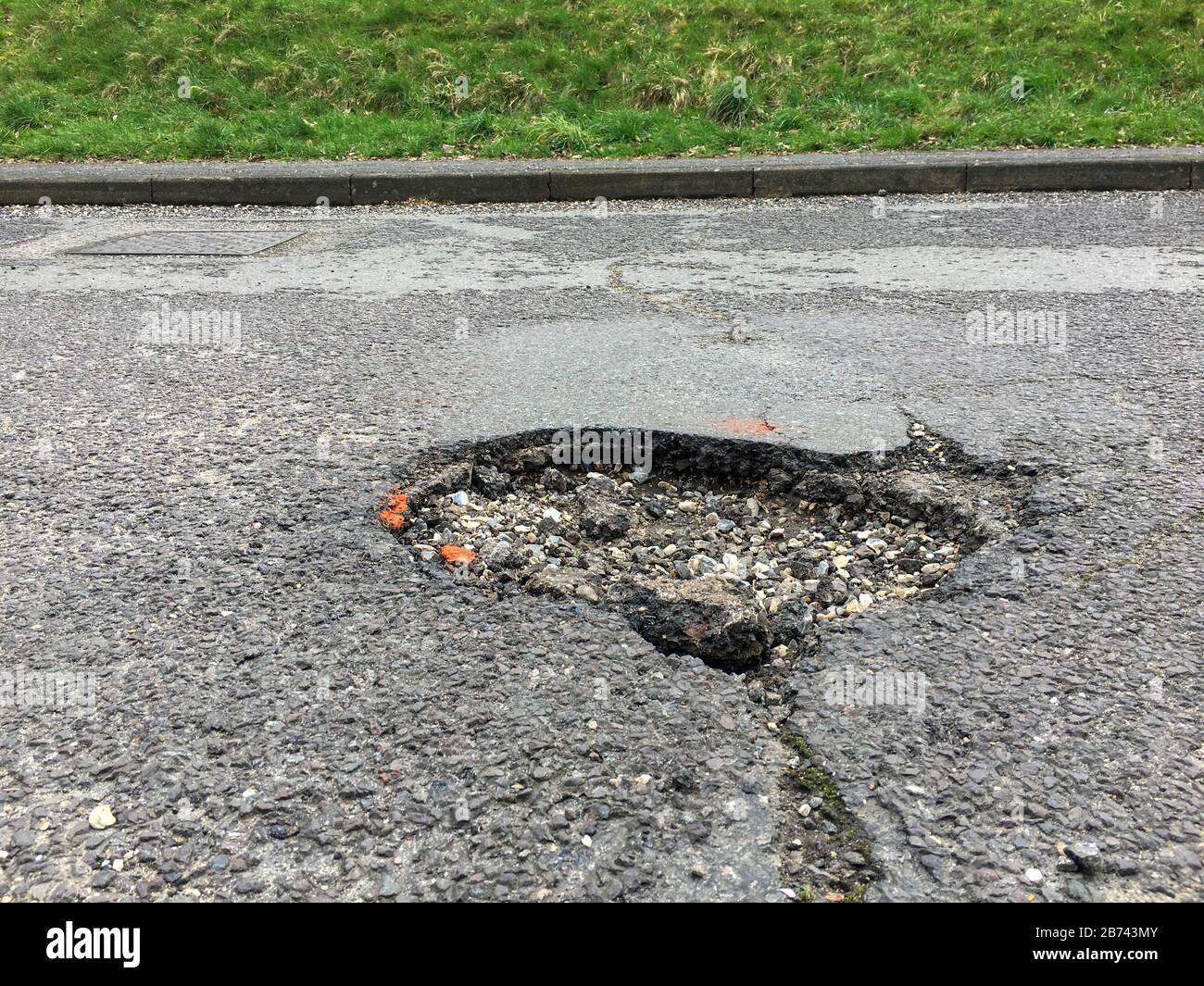A large pothole forms in a road surface in Godalming, Surrey, England ...