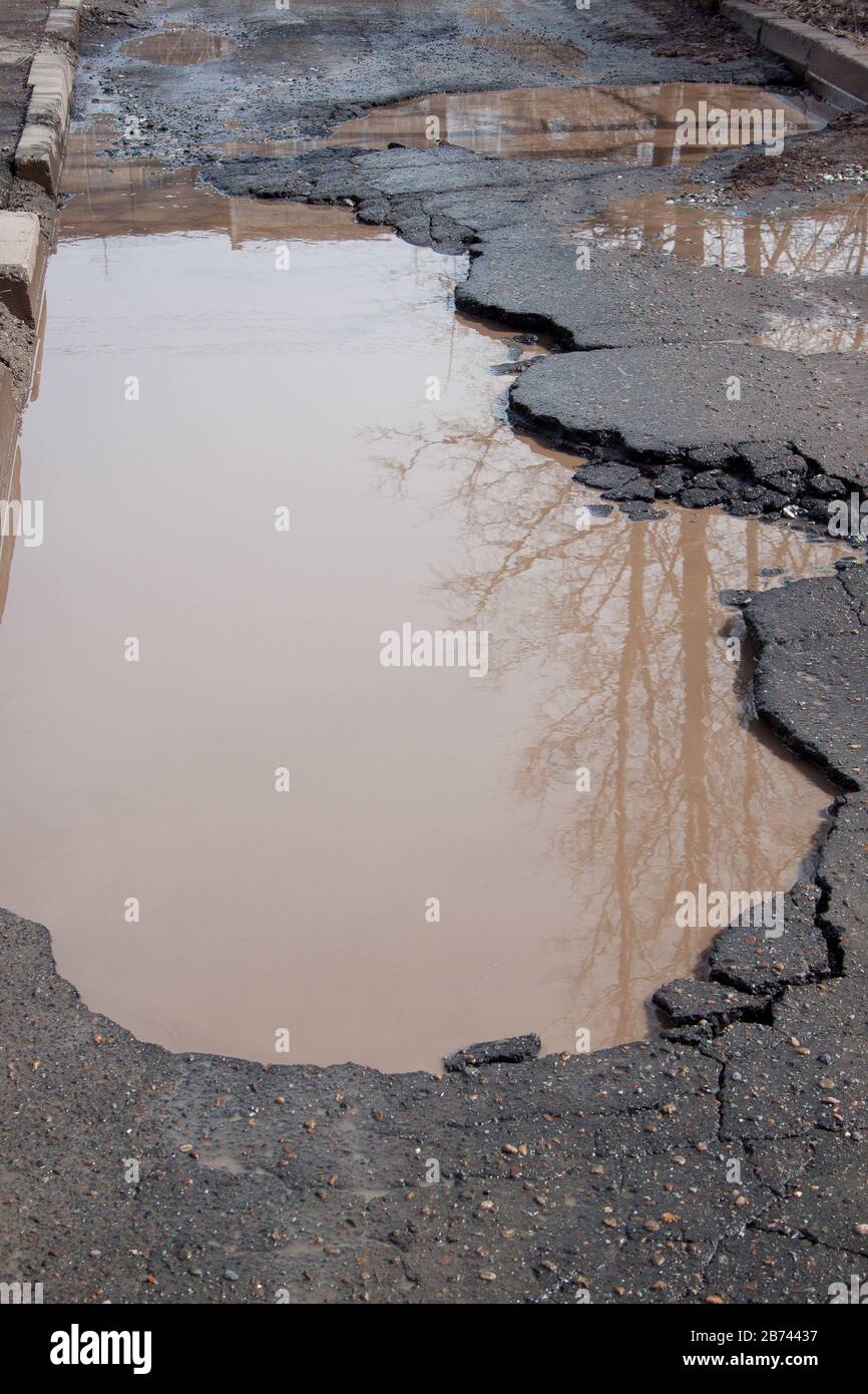 The bad asphalted road. Big pothole filled with water. Dangerous ...